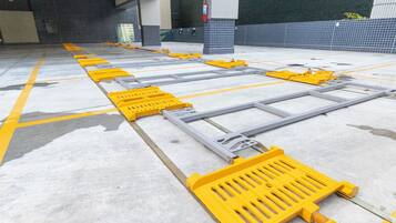 Uma garagem de estacionamento com barreiras amarelas e estruturas de metal cinzento no chão.