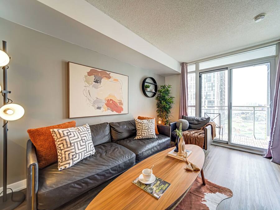 Uma sala de estar moderna com um sofá de couro, uma mesa de centro e uma janela grande com vista para a cidade.