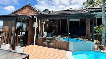 Um quintal com hidromassagem, deck de madeira e piscina.
