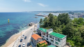 Um edifício à beira-mar com telhado verde, ao lado de uma praia e do oceano.