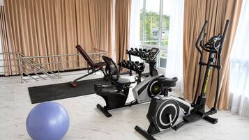 Uma academia em casa com equipamentos de exercícios, um tapete de yoga e uma bola de ginástica grande.