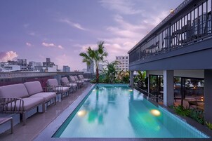 Piscina no terraço com espreguiçadeiras e vista para a cidade.