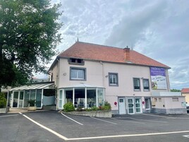 Um hotel com telhado de telhas vermelhas, uma placa indicando um restaurante e um estacionamento.