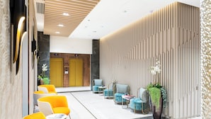 Um lobby moderno com áreas de estar, balcão de recepção e uma parede decorativa.