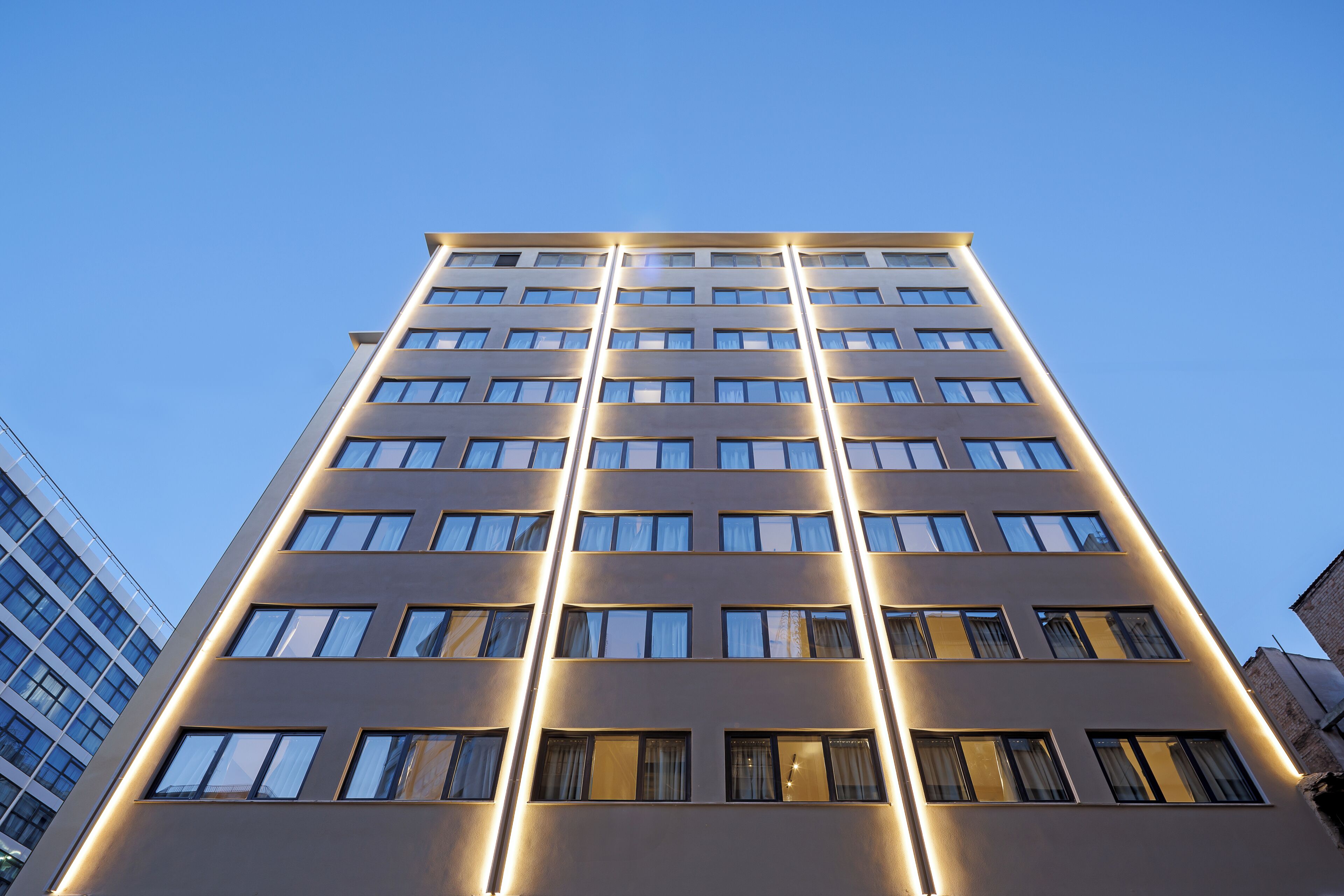 Um edifício alto e moderno, com grade de janelas e iluminado por luzes internas.