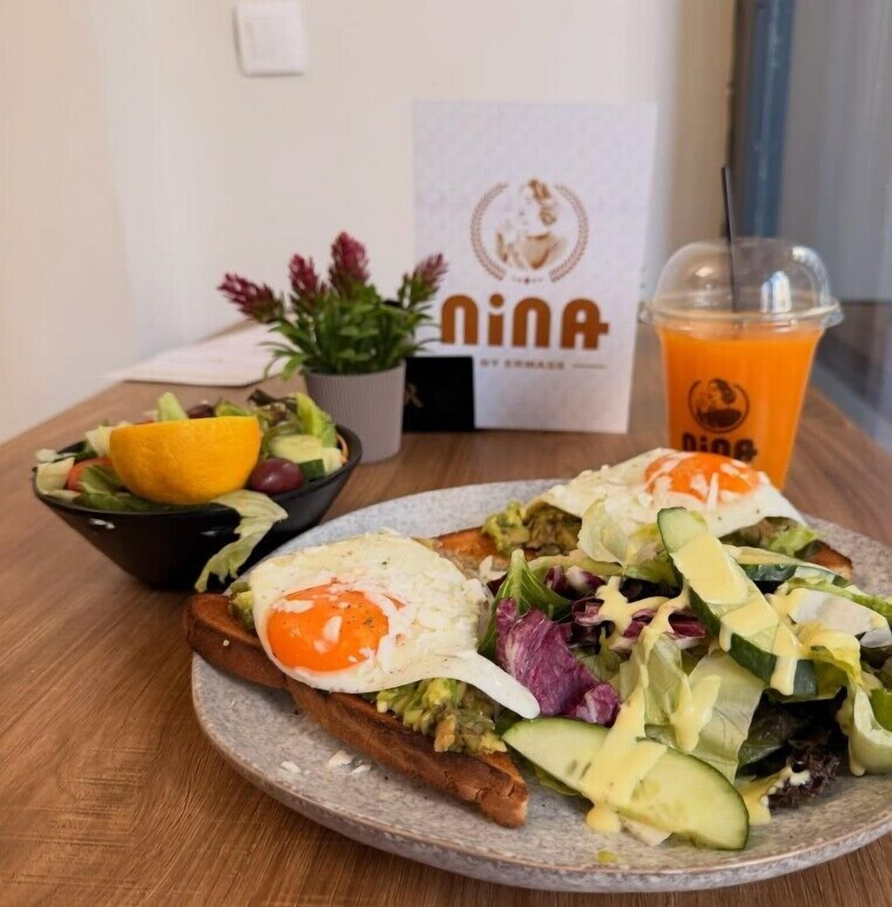 Uma refeição com salada, sanduíche e bebida sobre uma mesa.
