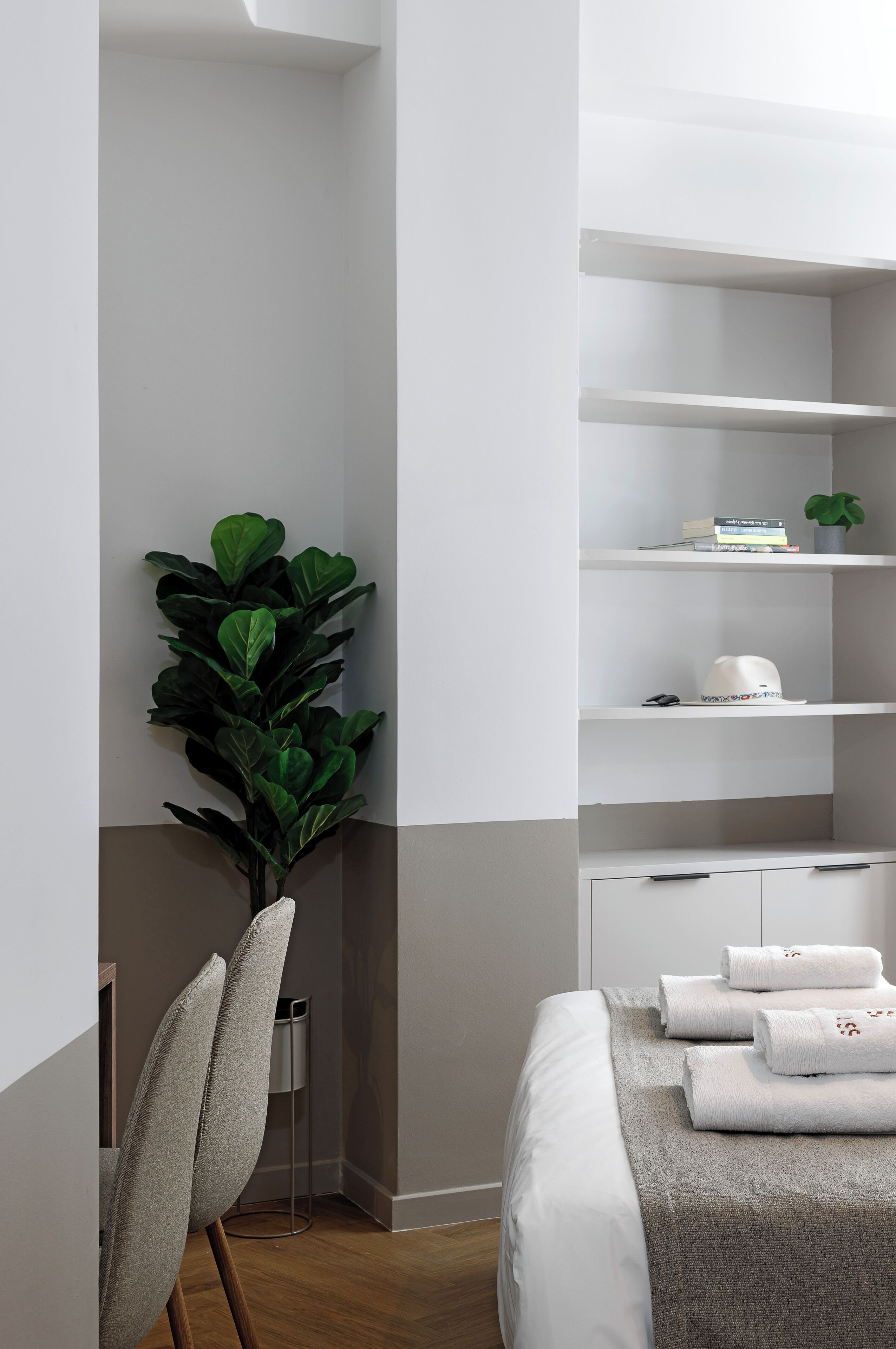 Um quarto moderno com cama, mesas de cabeceira, uma cadeira, uma planta e uma estante.