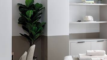Um quarto moderno com cama, mesas de cabeceira, uma cadeira, uma planta e uma estante.