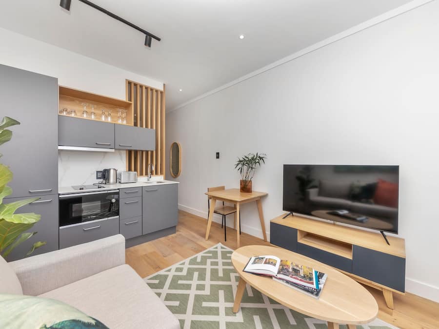 Um espaço moderno de estar com cozinha, área de jantar e televisão.
