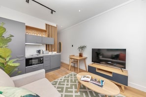 Um espaço moderno de estar com cozinha, área de jantar e televisão.