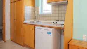Cozinha com armários de madeira, uma geladeira branca e uma janela acima da pia.
