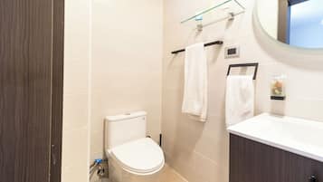 Uma casa de banho moderna com sanita, lavatório e duas toalhas penduradas num porta-toalhas.