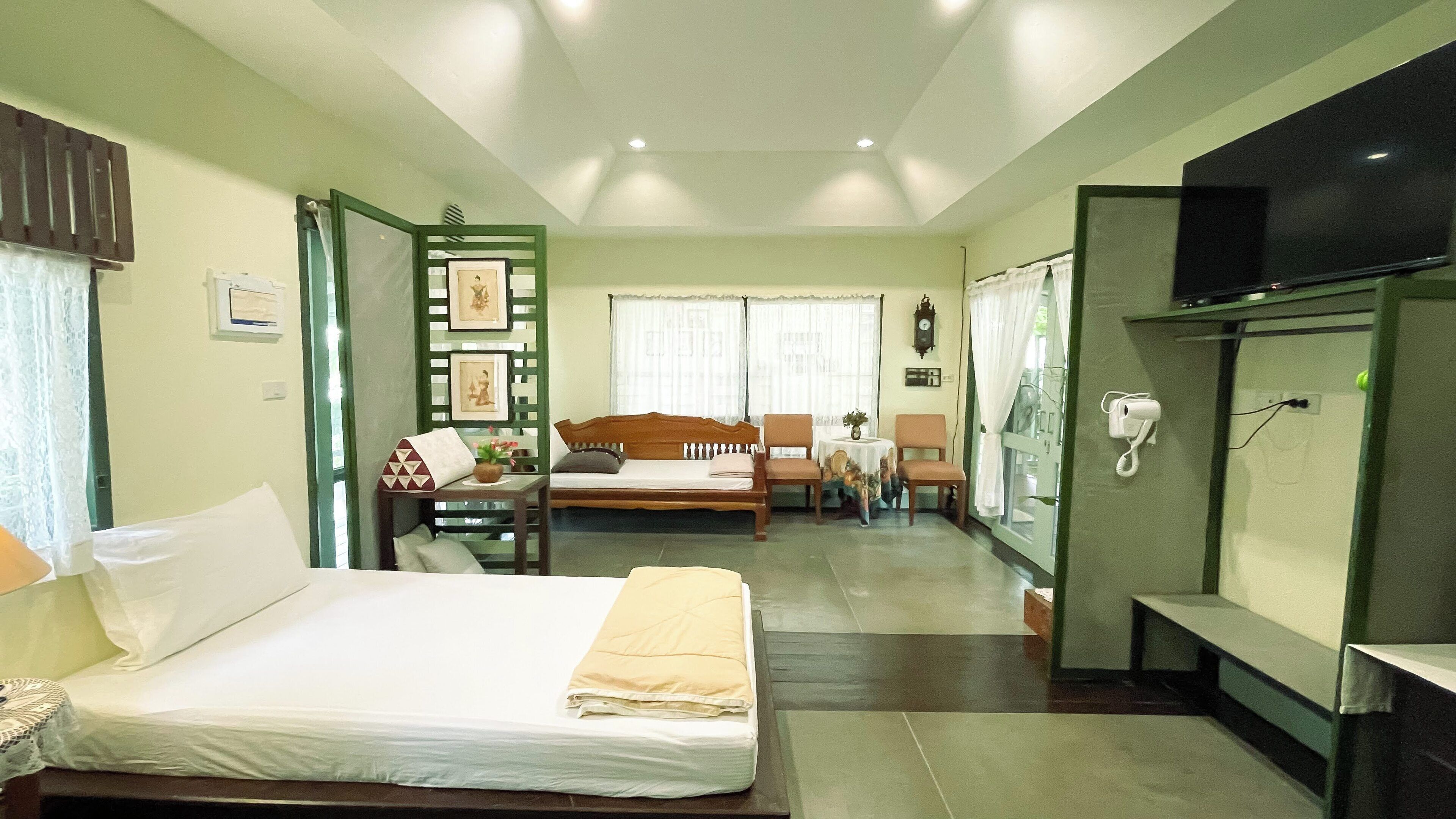 Quarto de hotel com cama, escrivaninha, cadeira, televisão e banheiro.
