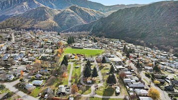 Zona residencial com casas, um campo verde e montanhas ao fundo.