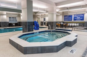 Uma área de piscina de hotel com hidromassagem, espreguiçadeiras e um espaço para relaxar.