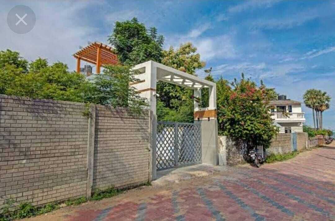 Área residencial murada, com muro de tijolos, pérgola de madeira e portão branco.