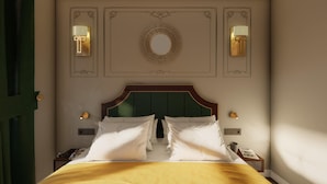 Uma cama bem arrumada com lençóis brancos e cabeceira verde, duas luminárias de cabeceira, um espelho fixado na parede e um objeto decorativo na parede.