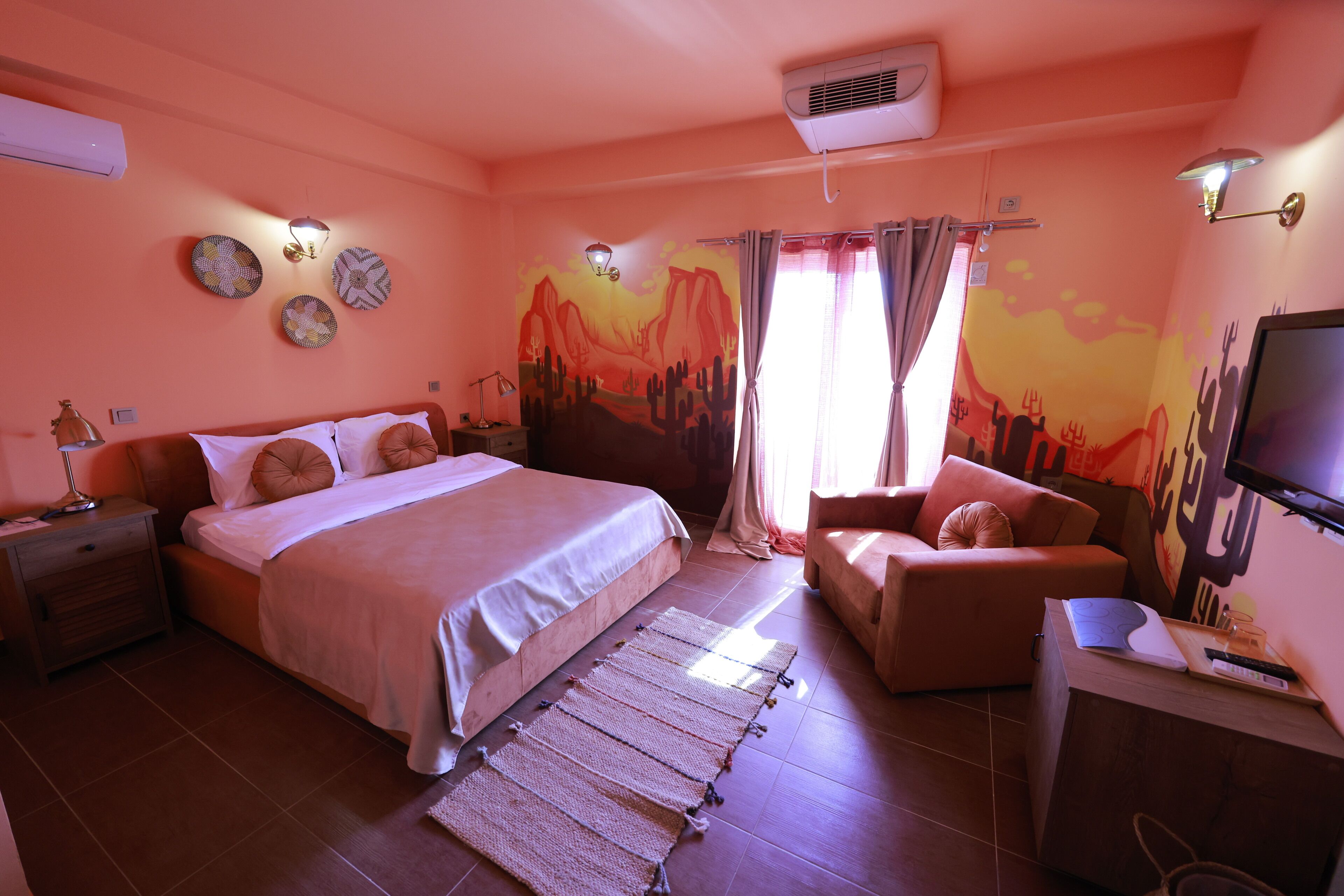 Quarto com cama, sofá, escrivaninha e televisão.
