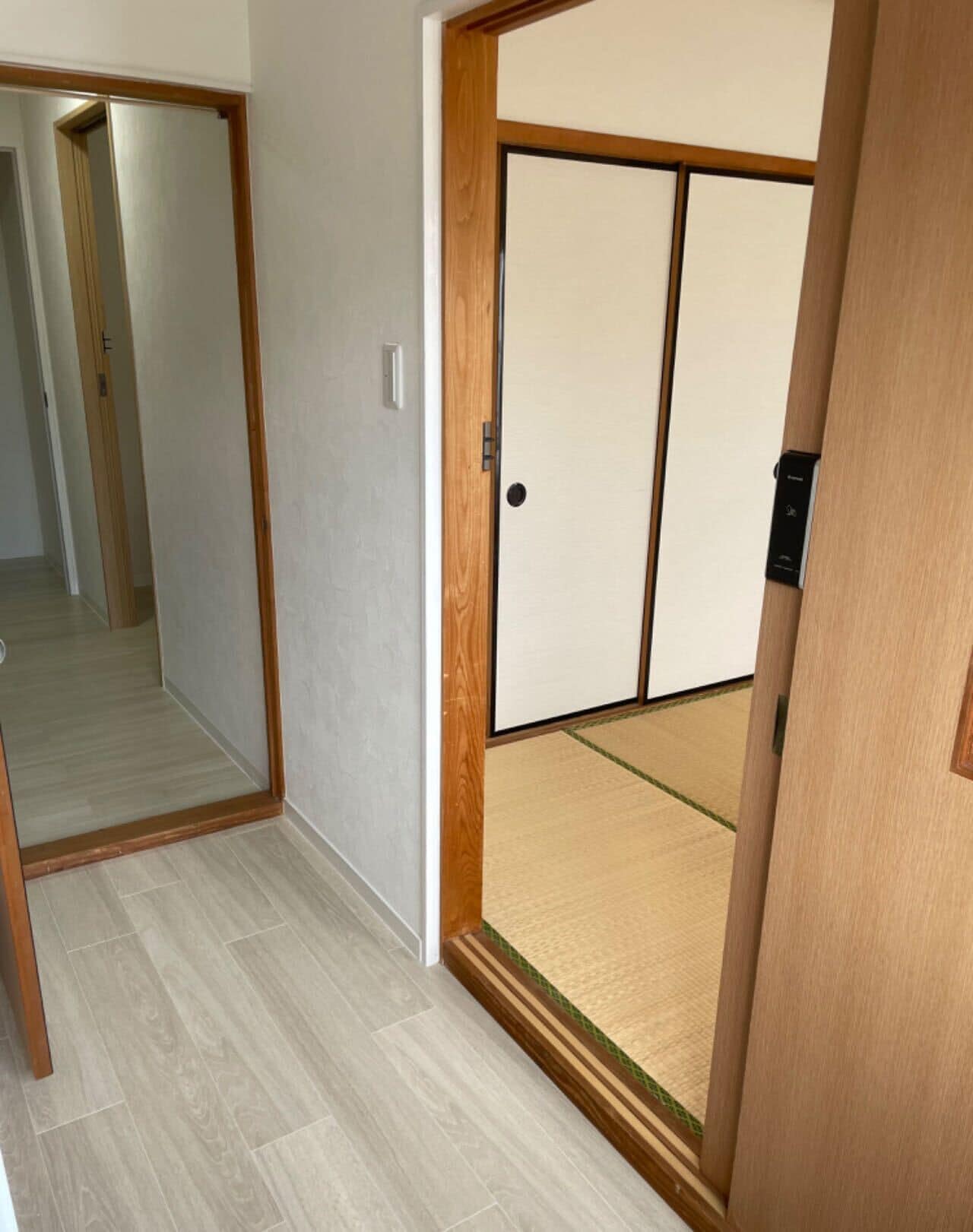 Quarto com piso de madeira, porta deslizante e interruptor de luz visível.