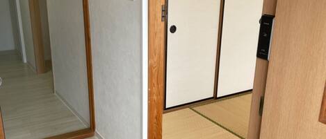Quarto com piso de madeira, porta deslizante e interruptor de luz visível.