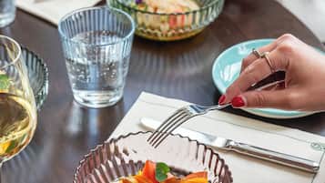 Uma mesa de jantar com uma saladeira, copos de vinho e um garfo.