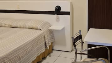 Quarto com cama, mesa de cabeceira, cadeira e escrivaninha.