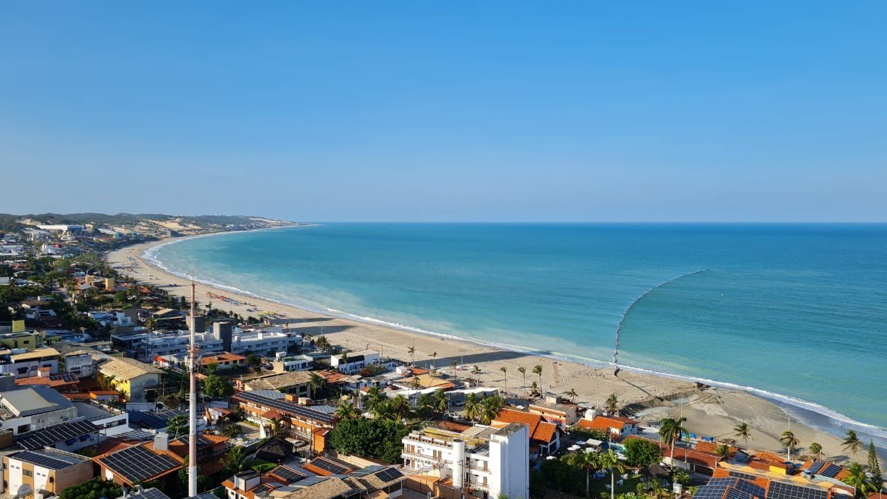 Uma vila costeira com praia, edifícios e céu claro.