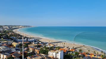 Uma vila costeira com praia, edifícios e céu claro.