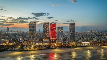 Paisagem urbana com arranha-céus, uma praia e um pôr do sol.