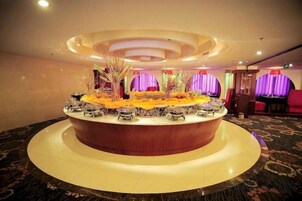 Uma área de recepção com balcão central, espaço de estar e arranjo decorativo de plantas.