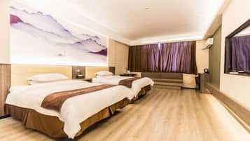Quarto de hotel com duas camas, um mural grande na parede, um sofá e uma televisão.