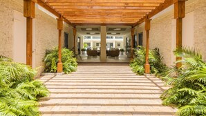 Uma galeria coberta com piso de tijolos, colunas de madeira e plantas em vasos.