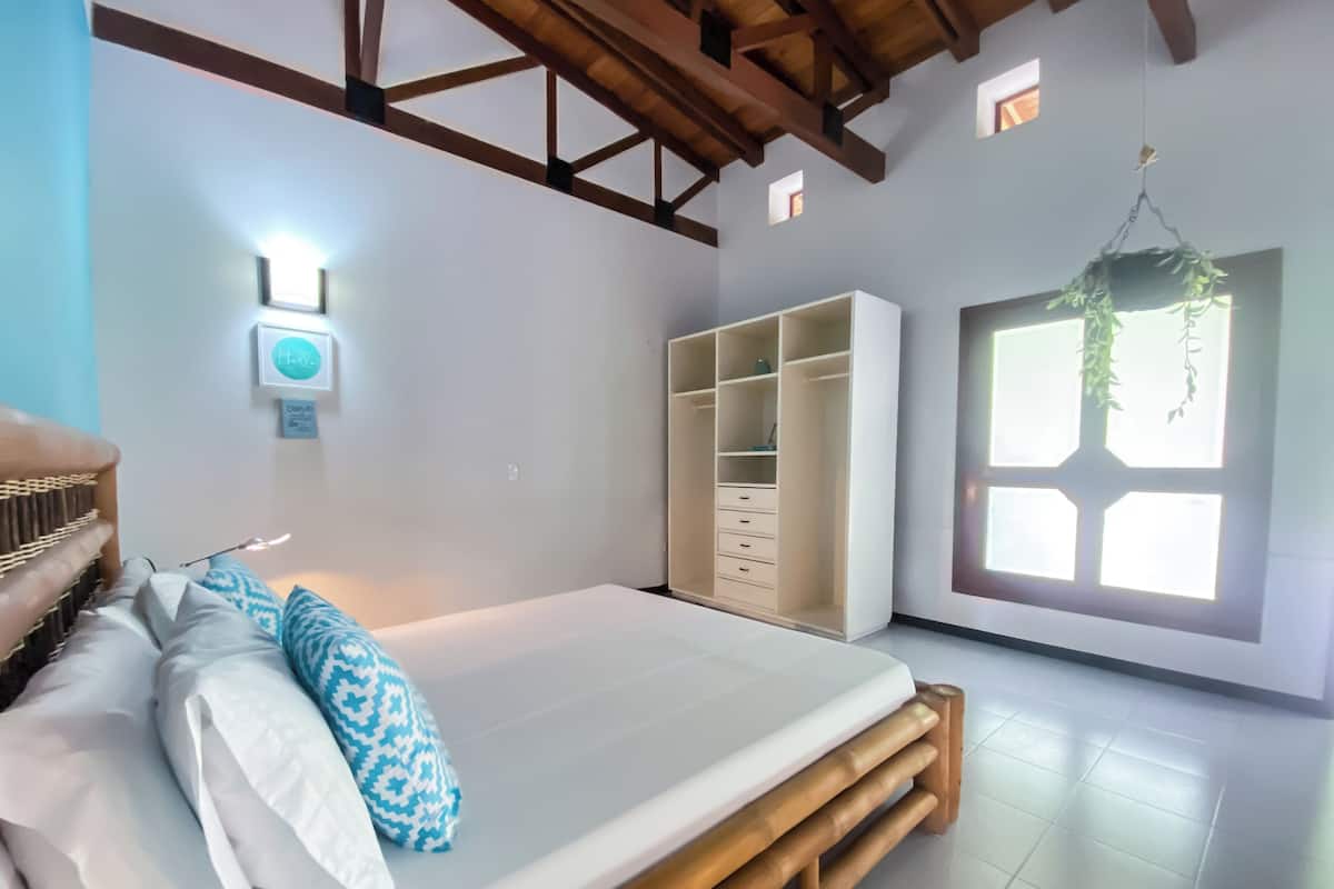 Quarto com cama, guarda-roupa, planta pendente e janela.