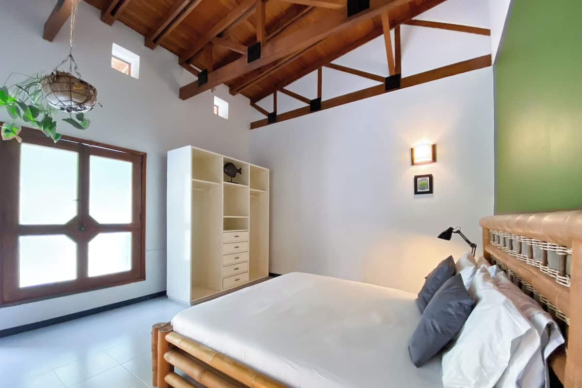 Quarto com cama, guarda-roupa e janela com vista.