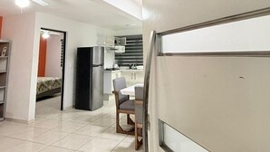 Cozinha ampla com eletrodomésticos modernos, sala de jantar com mesa e cadeiras, e um número de porta visível.
