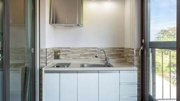Cozinha moderna com pia de aço inoxidável, armários brancos e painel decorativo com azulejos estampados.
