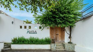 Uma villa com fachada branca, porta de madeira e pequena escadaria que leva à entrada.