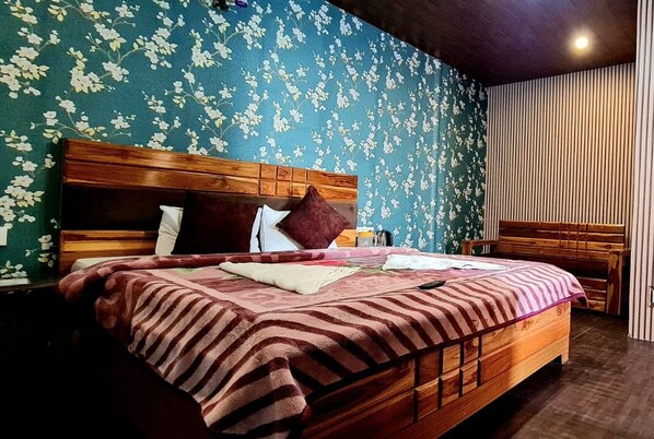 Cama bem arrumada com manta listrada, cabeceira de madeira e parede com papel de parede floral.
