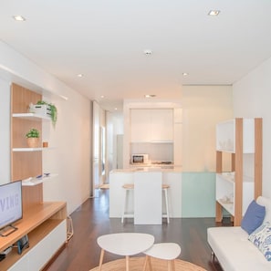 Uma sala de estar moderna com televisão, área de jantar e cozinha.