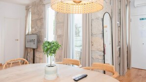Mesa de jantar redonda com planta em vaso no centro, um controle remoto e um pendente de luz com textura.