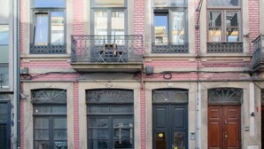 Um edifício de vários andares com fachadas rosa e bege, grandes janelas e varandas com grades de metal.