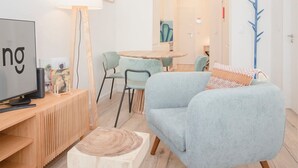 Uma sala de estar moderna com televisão de tela plana, mesa de consola de madeira, luminária de chão e poltrona azul claro.