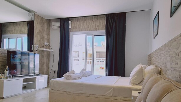 Quarto de hotel moderno com cama, sofá, televisão e vista para a cidade.