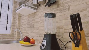 Uma cozinha com um liquidificador, uma fruteira e um bloco de facas.