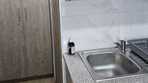 Cozinha com pia de aço inoxidável, dispensador de sabão e cesto de metal.