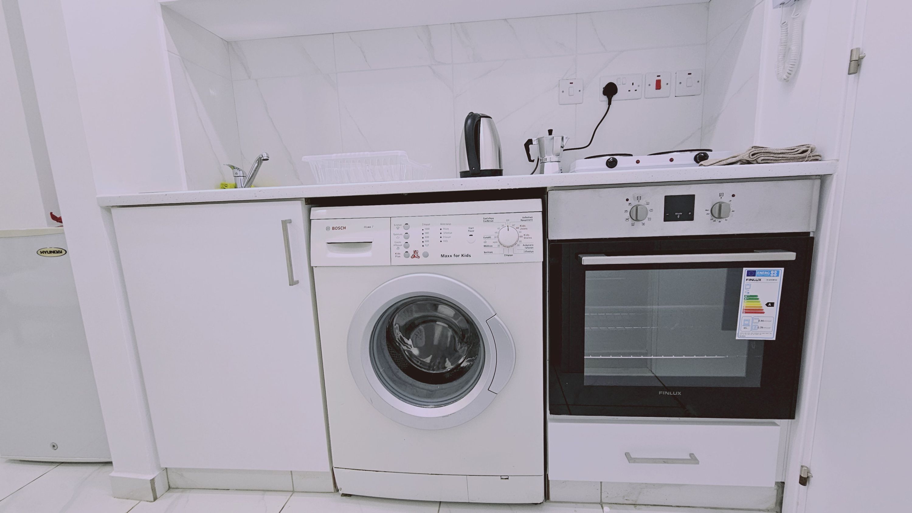 Uma lavanderia compacta com máquina de lavar Bosch e forno Finlux.