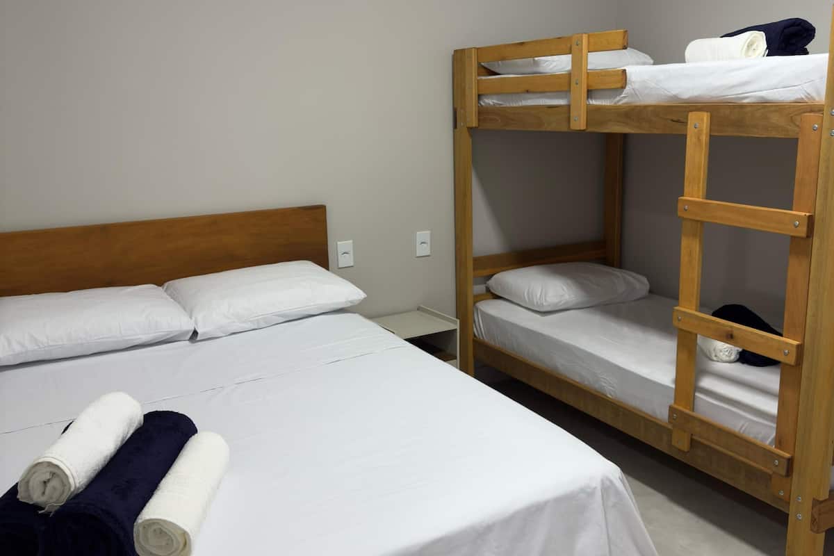 Quarto com beliche, incluindo uma cama de cima e uma cama inferior. Há toalhas e um cobertor enrolado na cama.