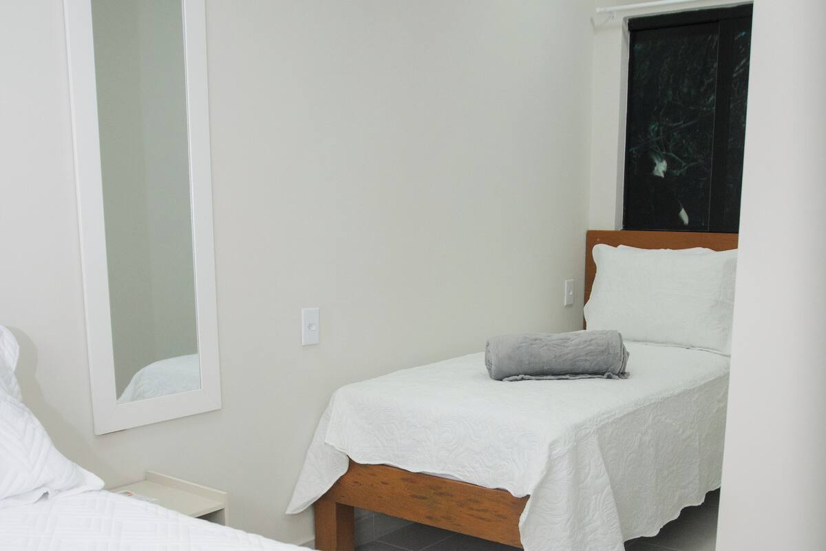 Quarto de hotel com duas camas, um espelho grande e um aparelho de ar condicionado.