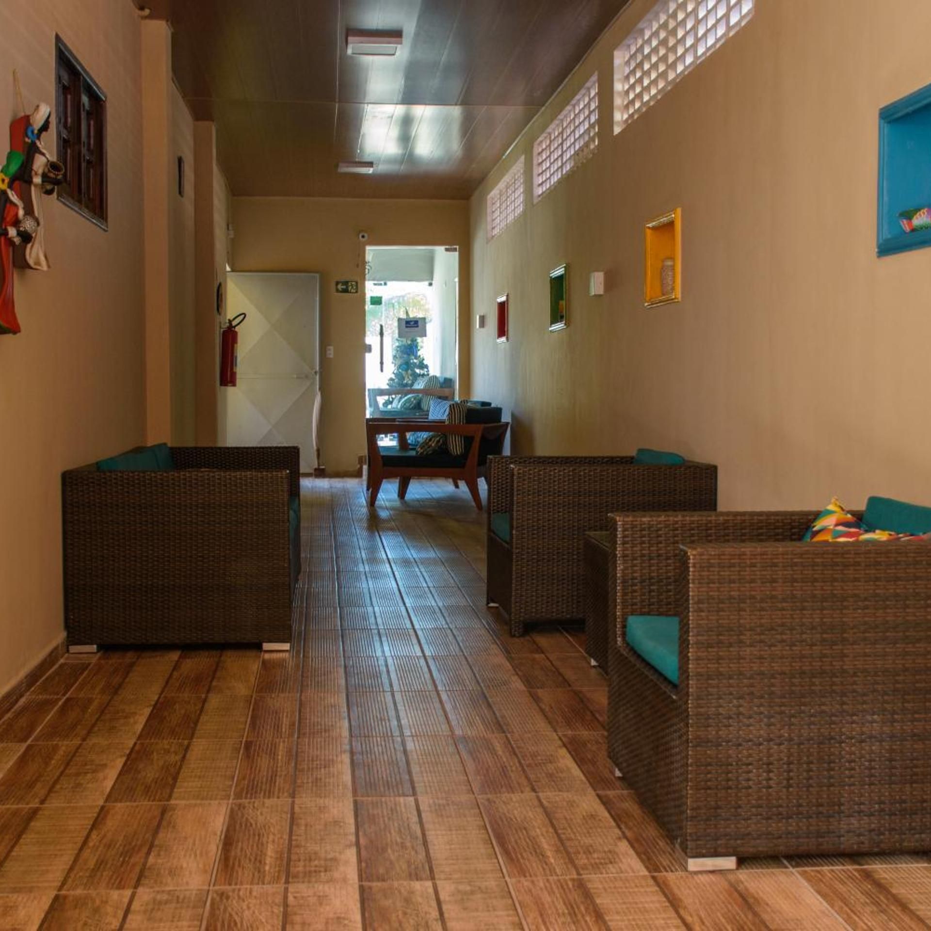 Corredor com mobiliário de vime, piso de madeira e vista para uma sala de jantar.