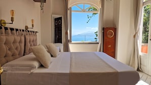 Quarto com uma cama grande, um guarda-roupa de madeira e vista para o mar.